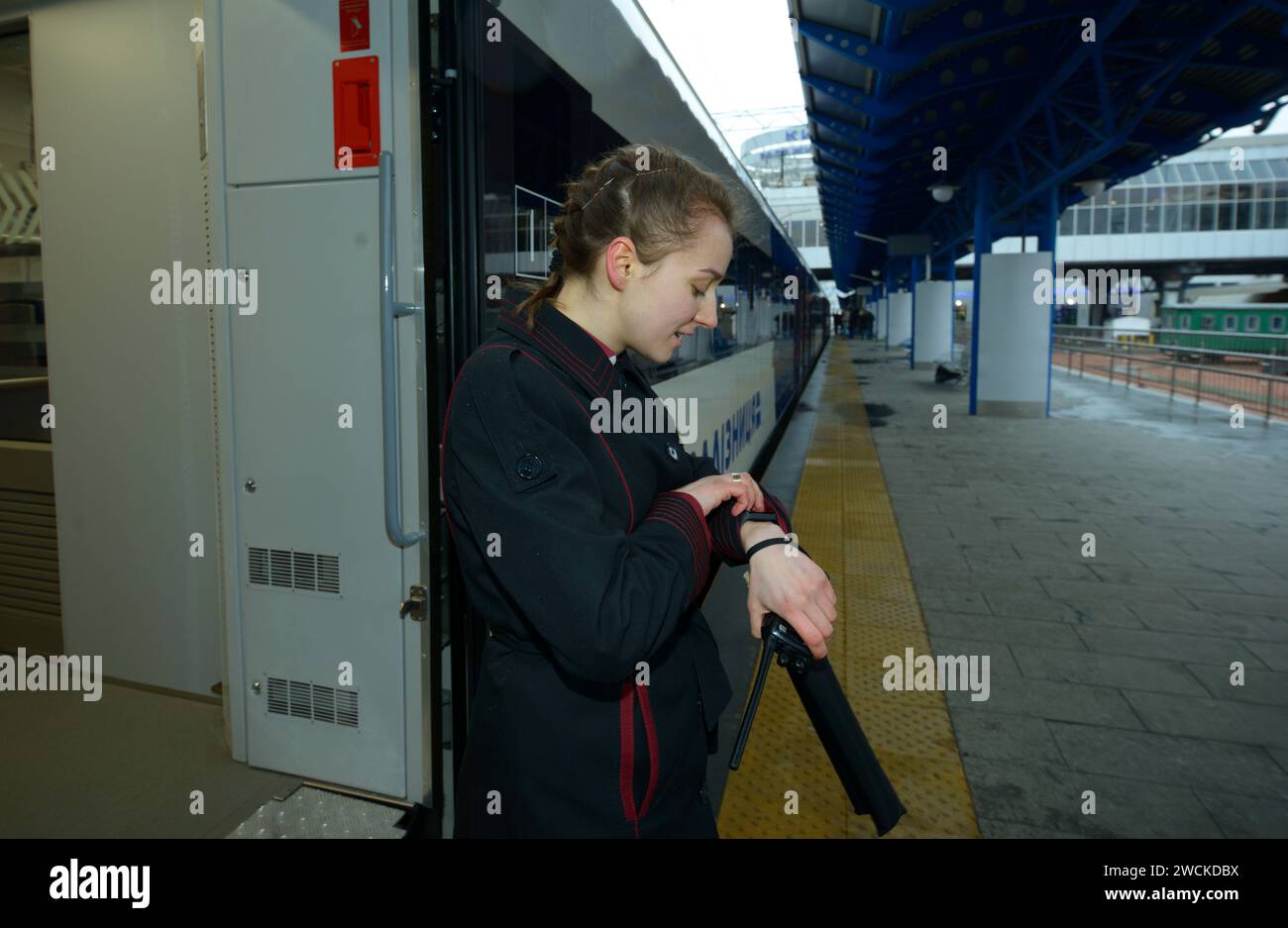 Young woman train conductor looking at her watch waiting for signal ...