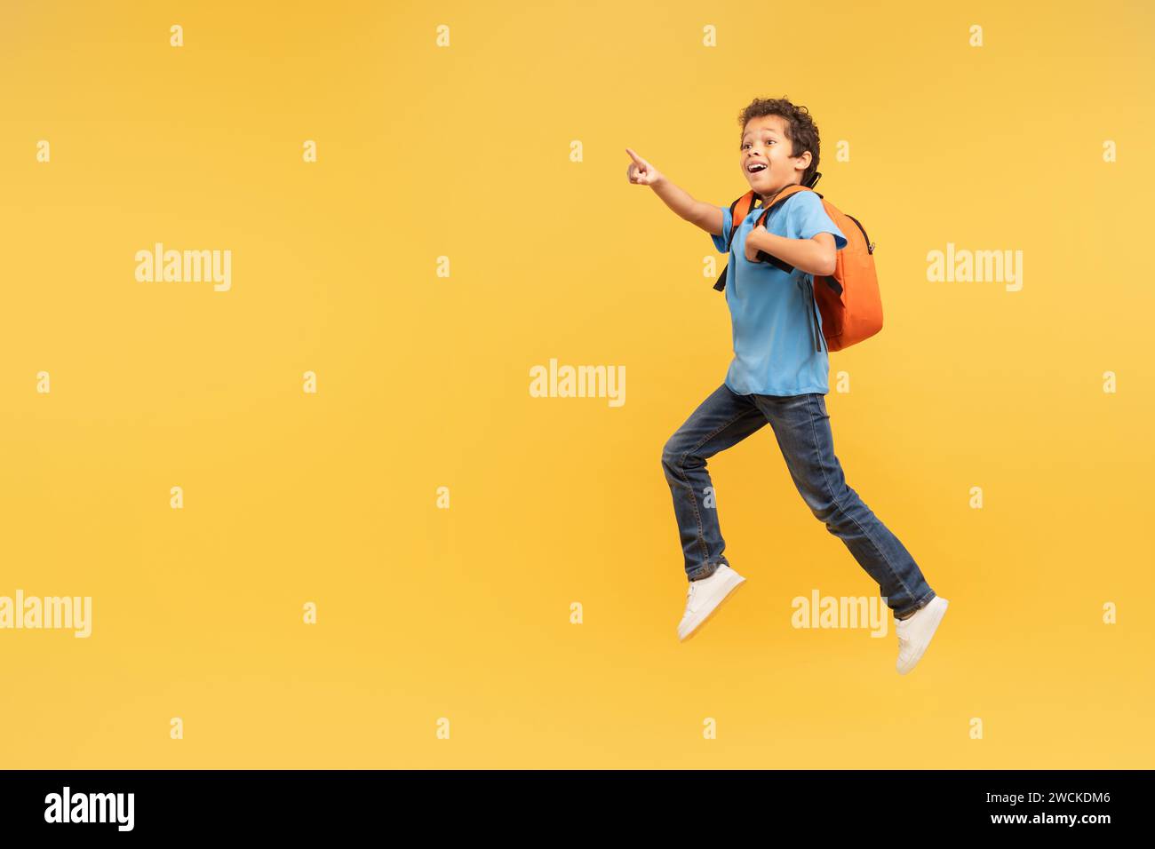 Boy in mid-stride pointing excitedly, yellow backpack Stock Photo - Alamy