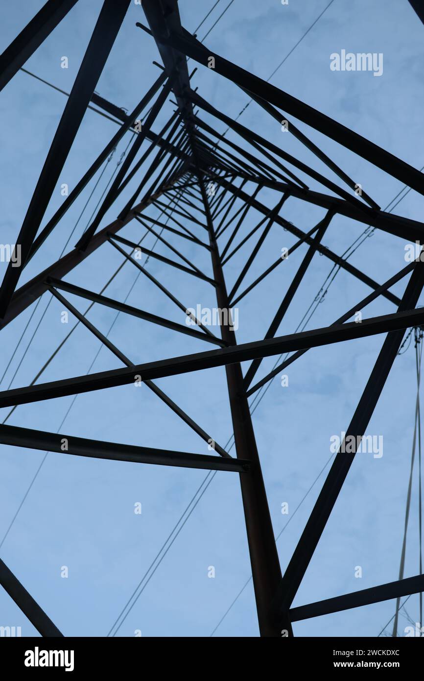 A low angle shot of a high-voltage power line under a bright blue sky ...