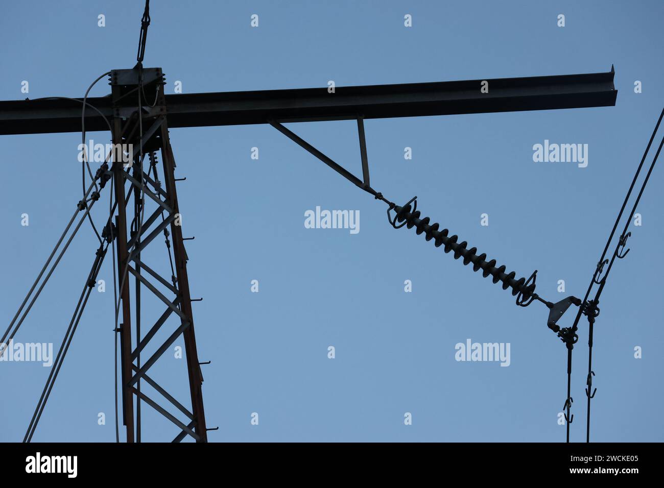 A low angle shot of a high-voltage power line under a bright blue sky ...