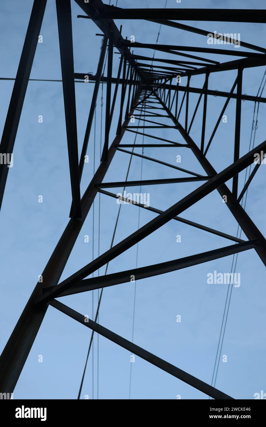A low angle shot of a high-voltage power line under a bright blue sky ...