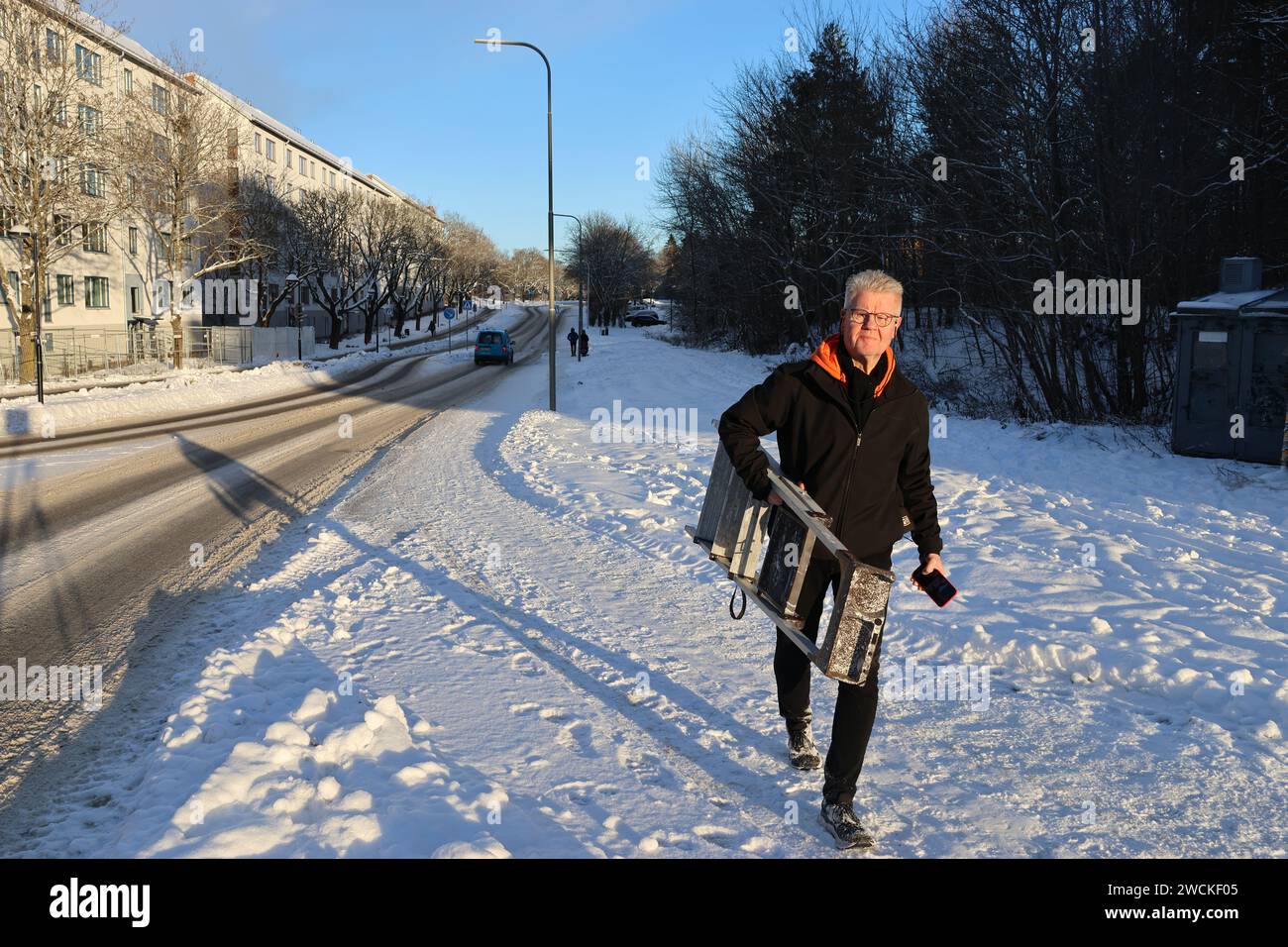 Winter and now on ground - man carries a folding ladder Stock Photo - Alamy