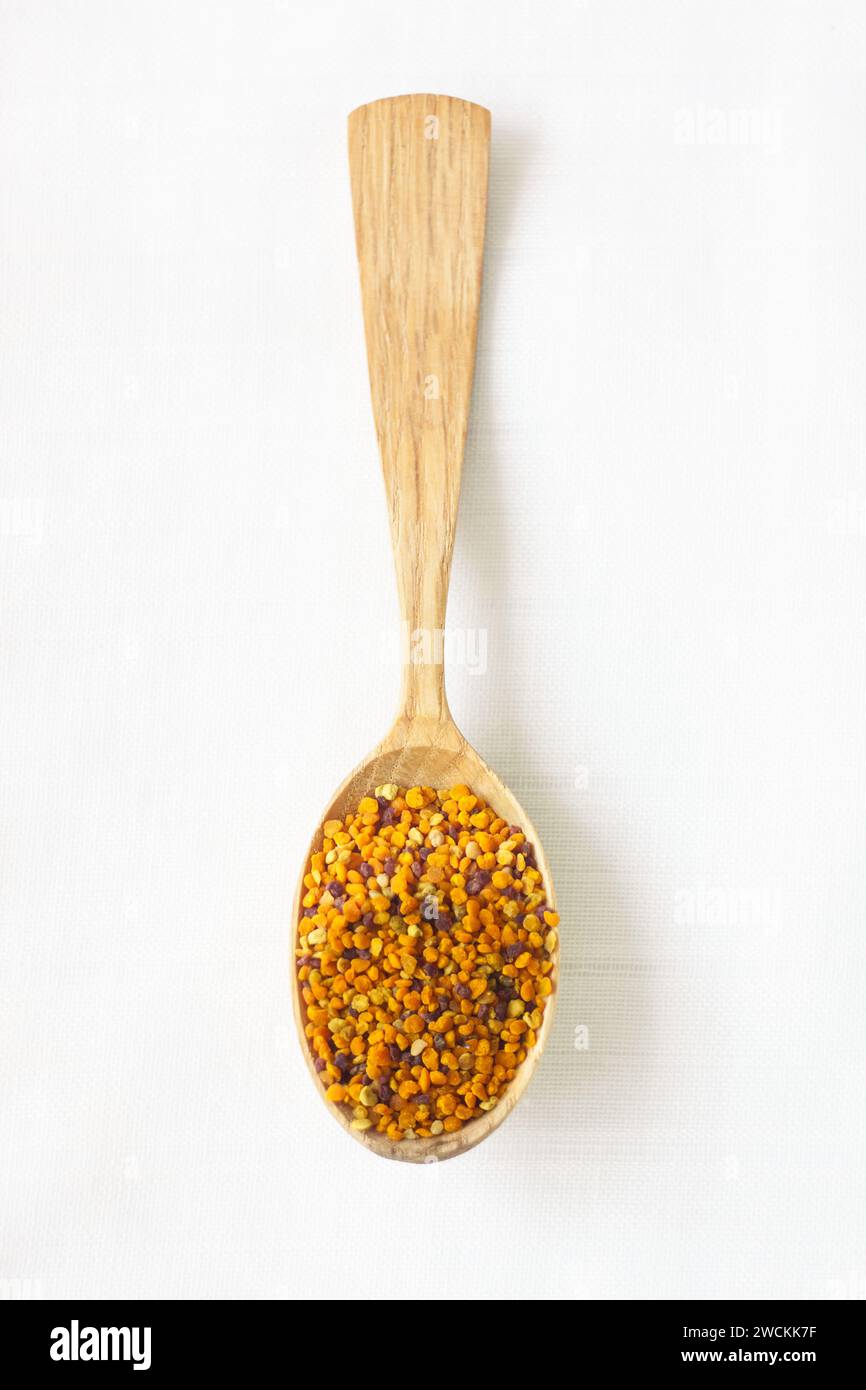 Bee pollen granules in a wooden spoon on white background. Superfood ...