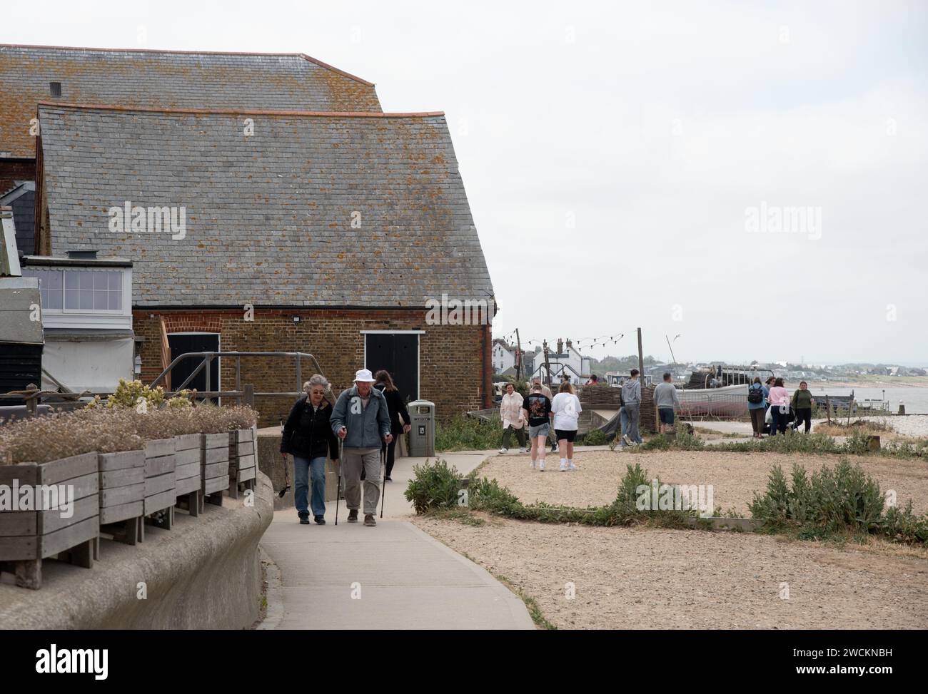 Tourists and locals walk along the seafront pathway seaside with ...
