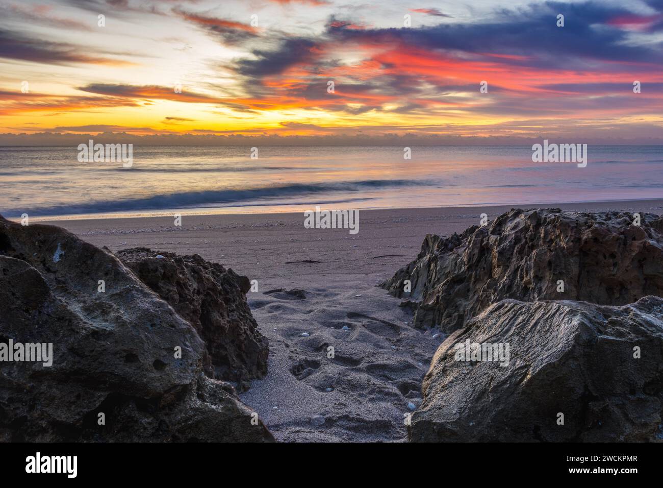 Dramatic beach sunrise with vivid clouds and rocky terrain, ideal for ...