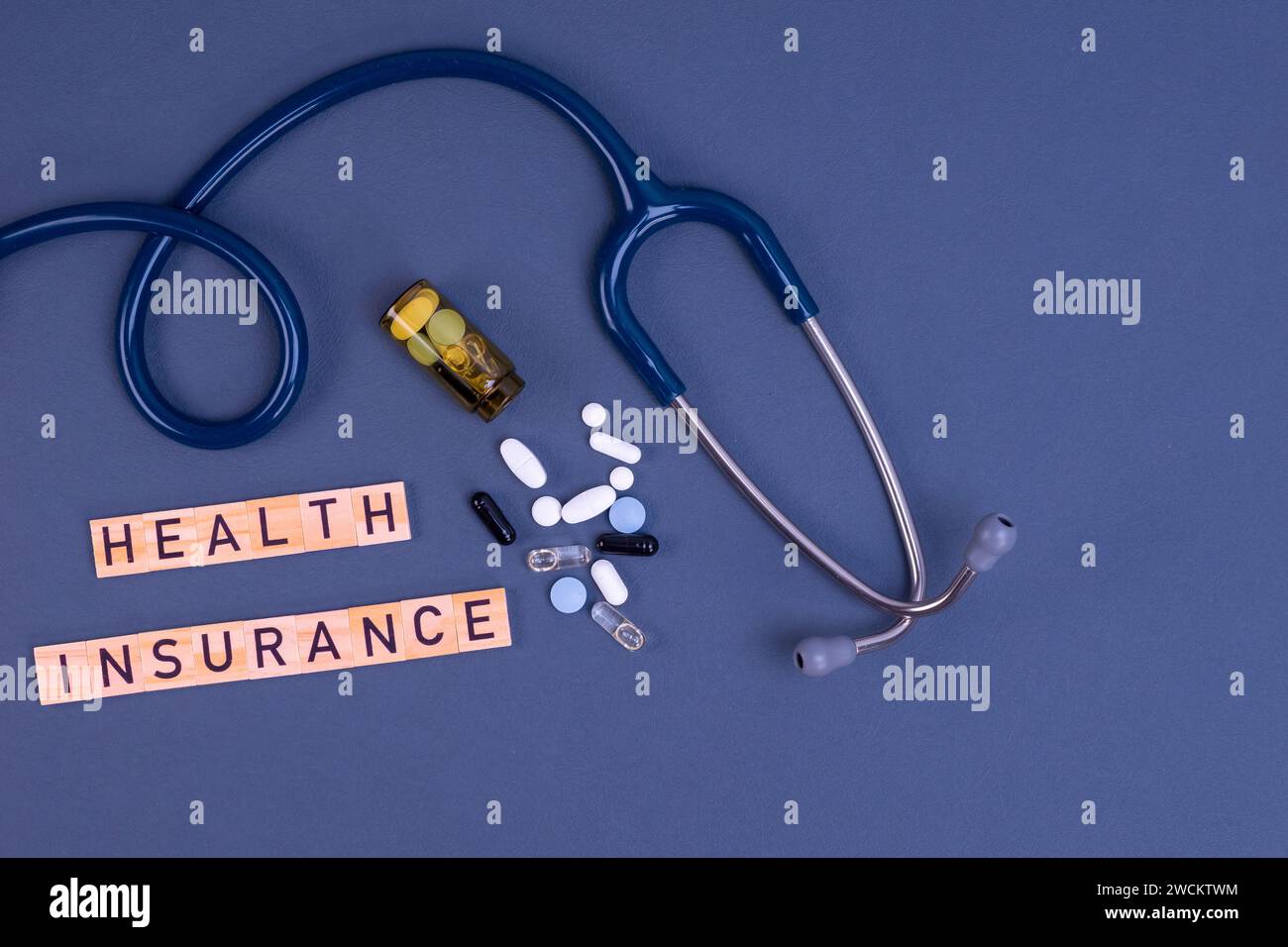 Health insurance text with stethoscope and pills on table. Medical ...