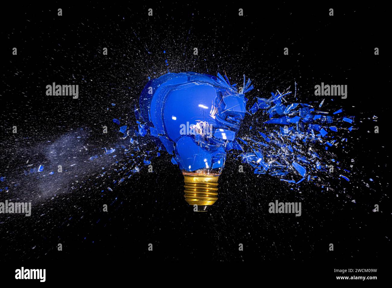 traditional blue bulb breaks and explodes on a black background. high ...
