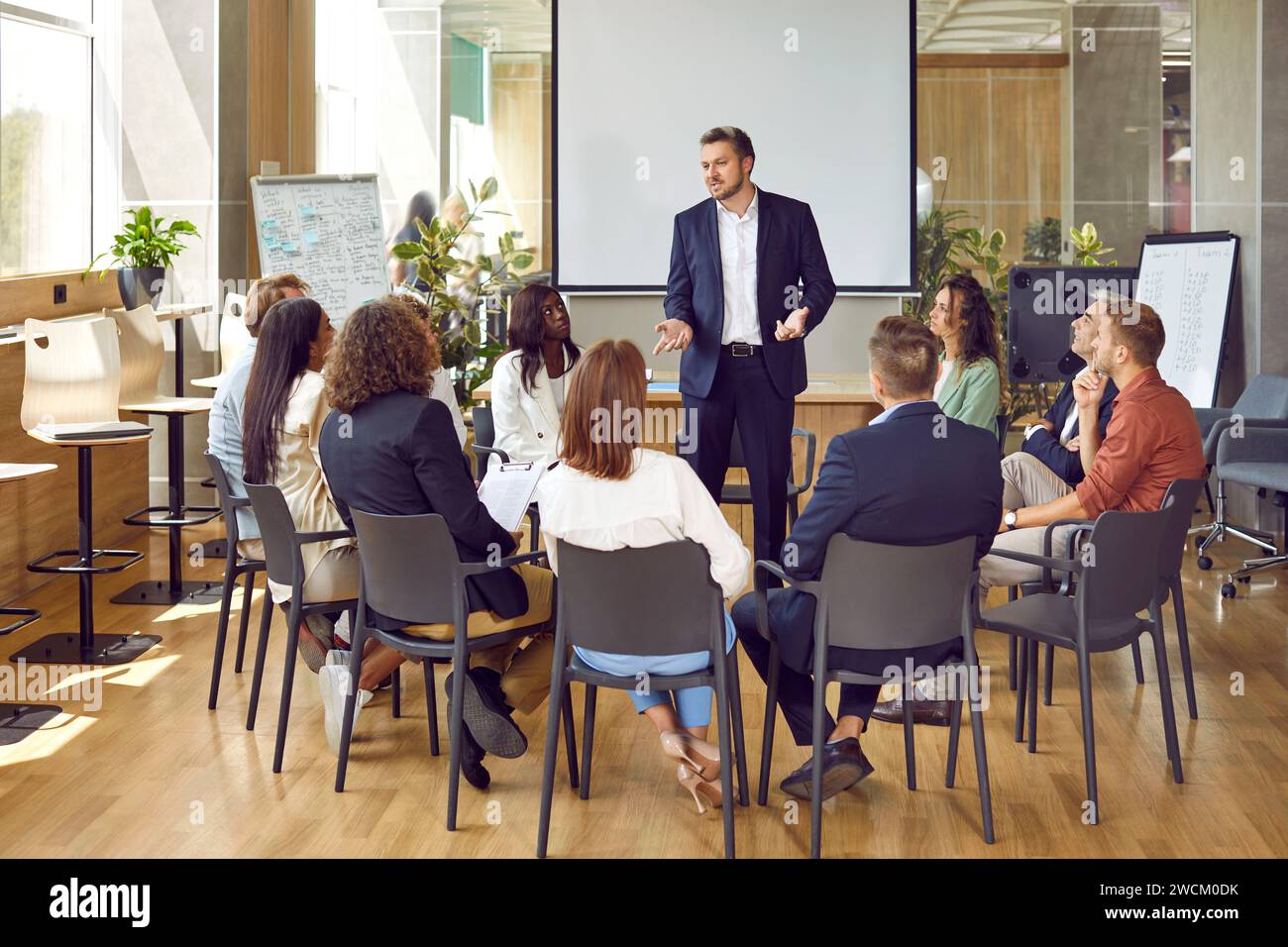 Serious business group leader instructing team, telling project ...