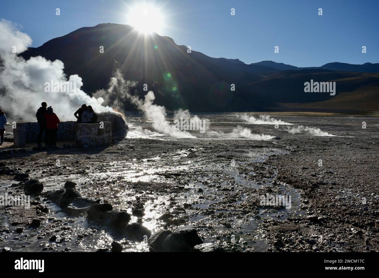 Steam rising from the ground behind rows of stones with the sun shining ...
