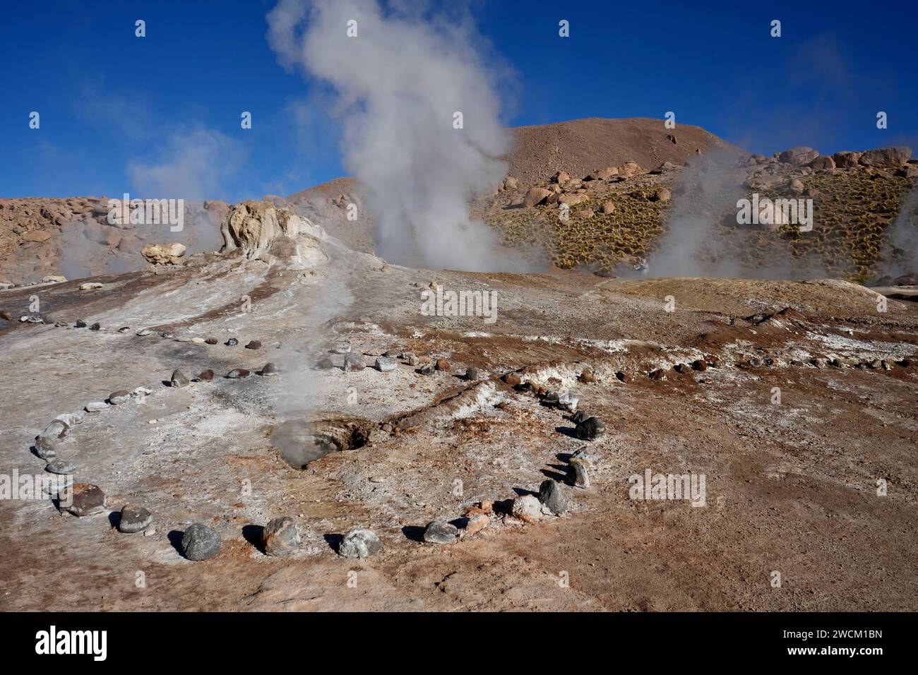 Steam rising from the ground with hills and blue skies behind, at ...