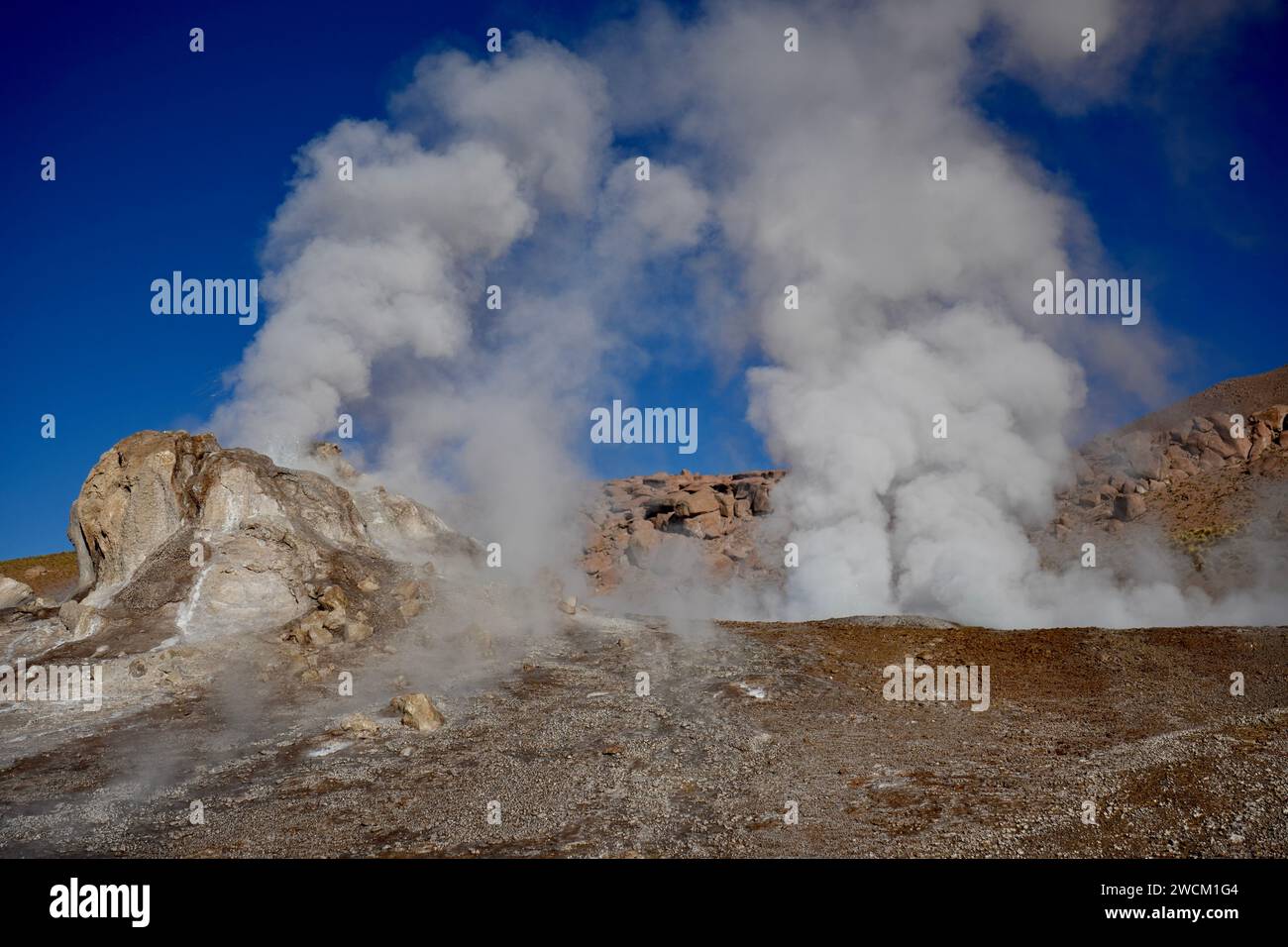 Steam rising from the ground with hills and blue skies behind, at ...