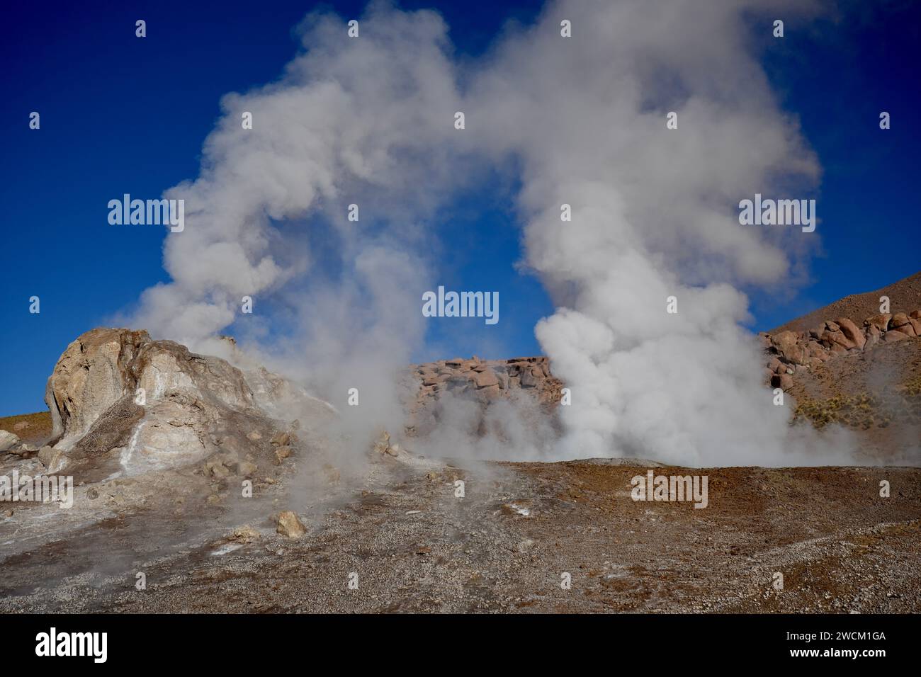Steam rising from the ground with hills and blue skies behind, at ...