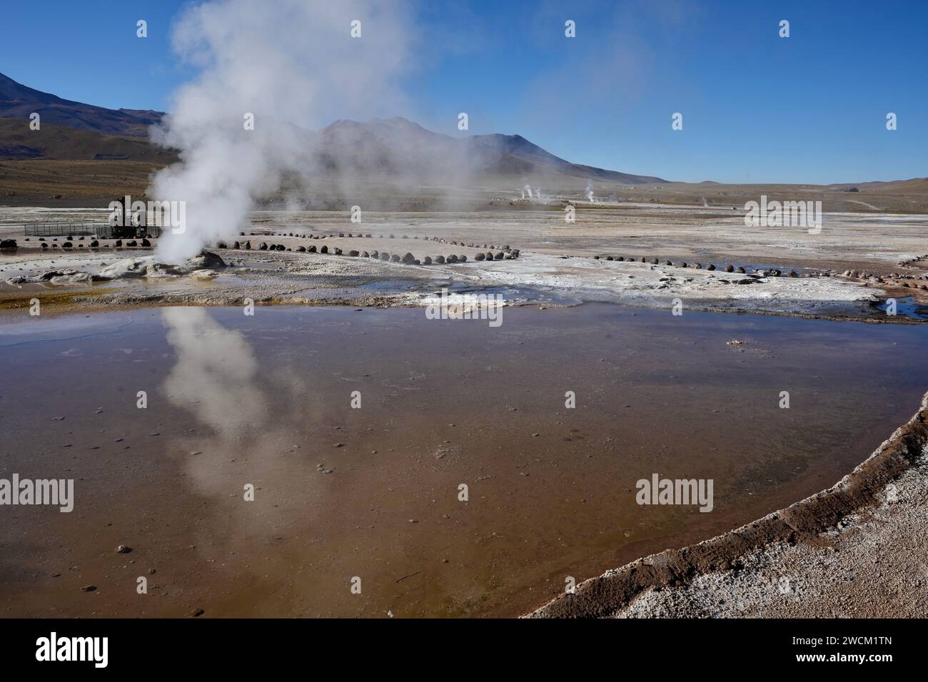 Steam rising out of the ground reflected in the lagoon with mountains ...