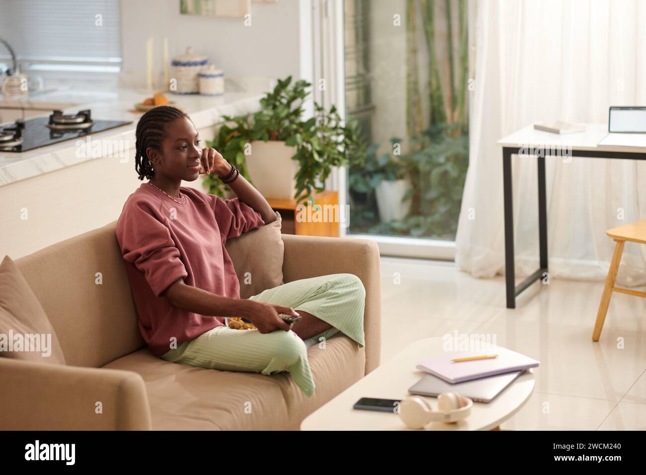 Bored teenage girl sitting on couch and watching true crime show Stock ...