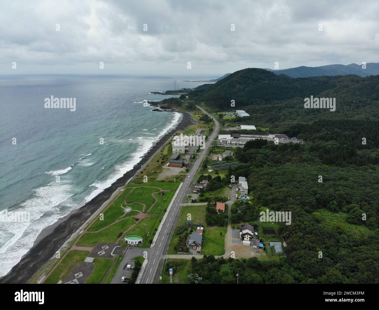 Serene Coastal Village by Verdant Mountain Range Stock Photo - Alamy