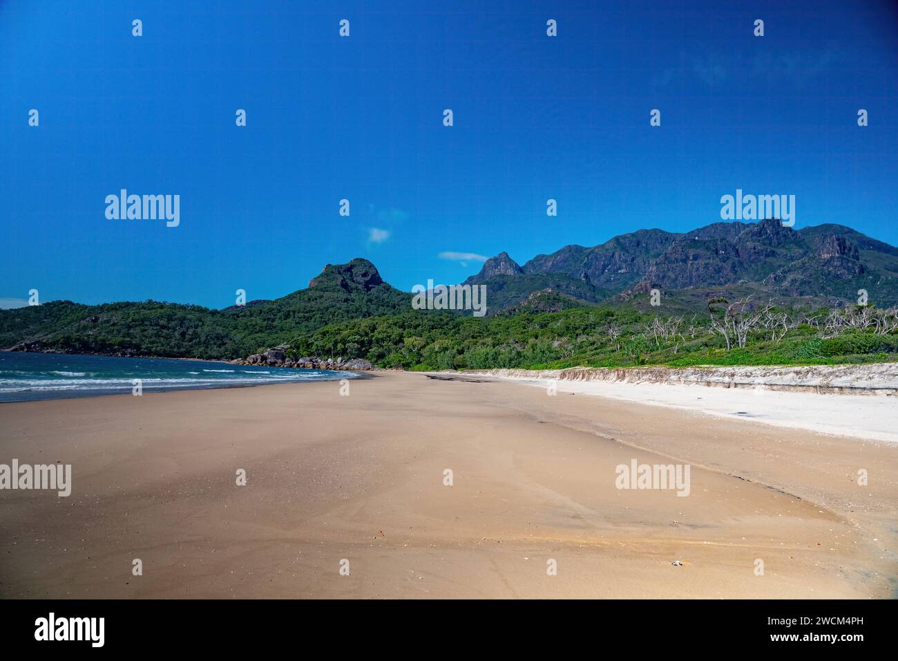 Scenic beach with blue sky and distant mountains Stock Photo - Alamy