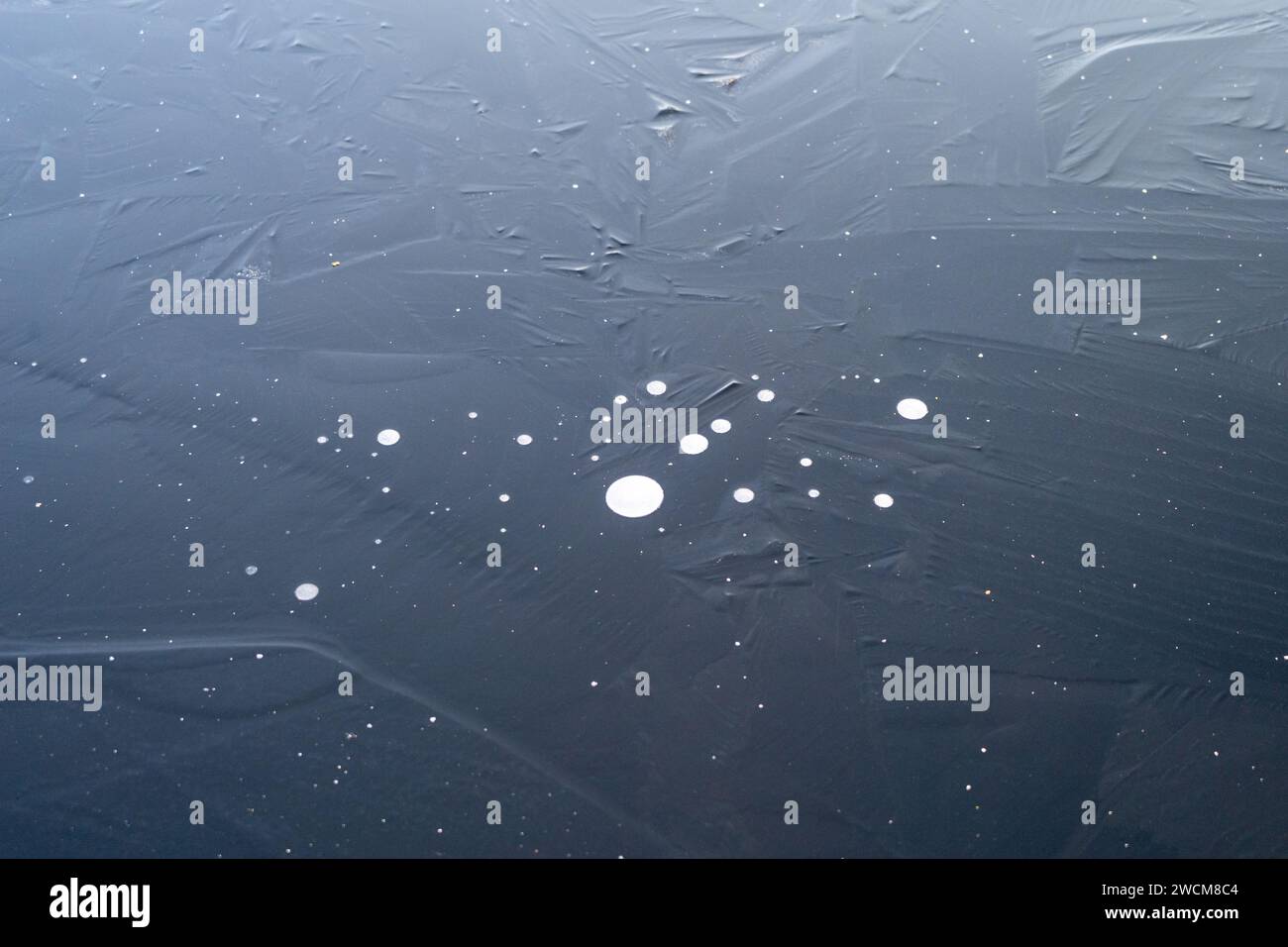Abstract icy patterns and water droplets on a dark surface, captured in ...