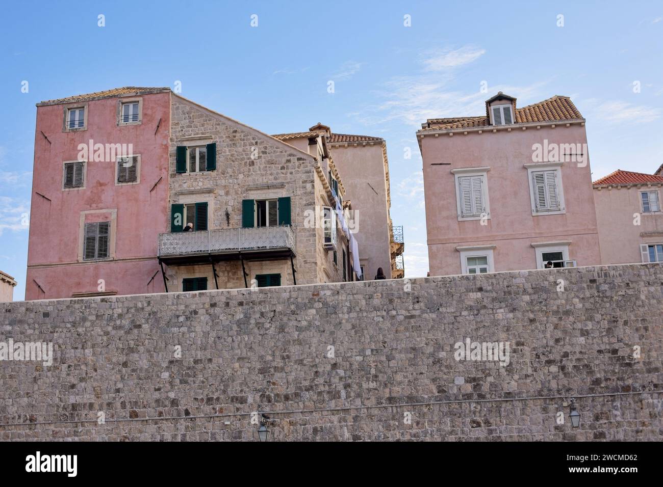Historic pastel-colored buildings rise above the fortified stone walls ...