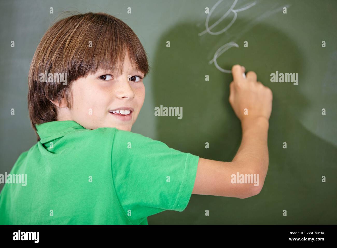 Portrait, happy and boy writing on a chalkboard for child development ...