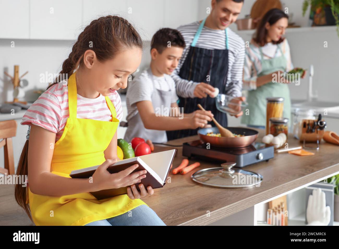 Little girl reading recipe book in kitchen Stock Photo - Alamy
