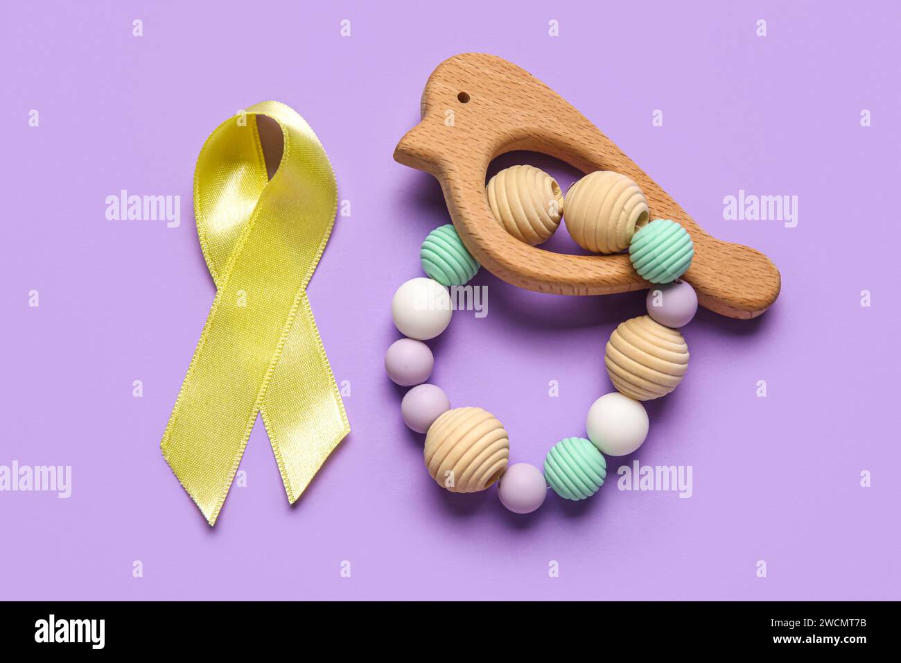 Golden ribbon with rattle on lilac background. Childhood cancer ...