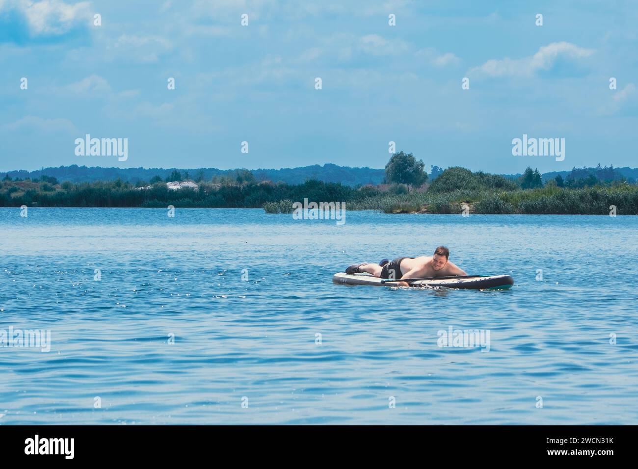 man sunbathing on supboard in the middle of the lake Stock Photo - Alamy