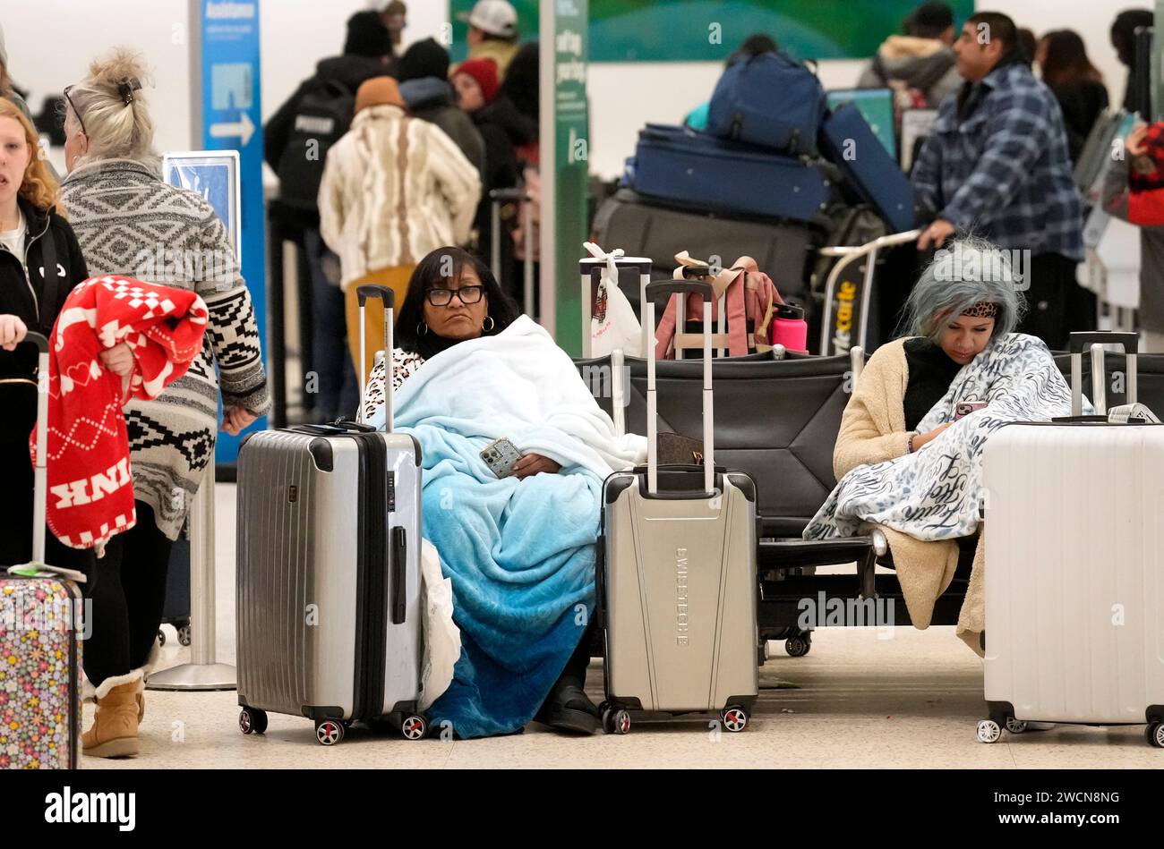 Ana Rosario of Houston, sitting left, tries to keep warm as she waits ...