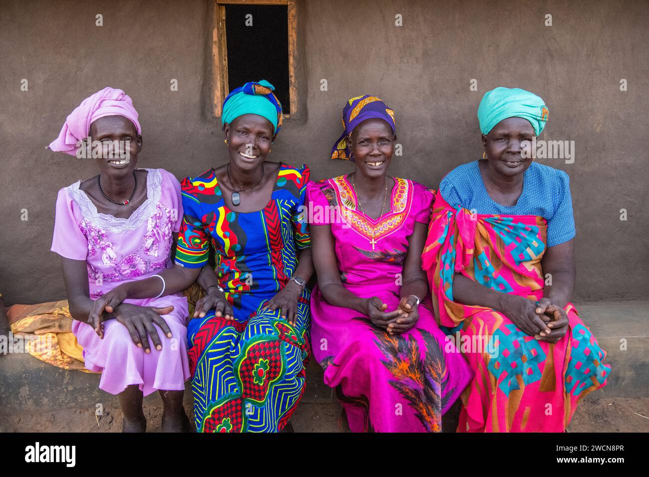Uganda, Adjumani. Women dressed up for church relax outside of their ...