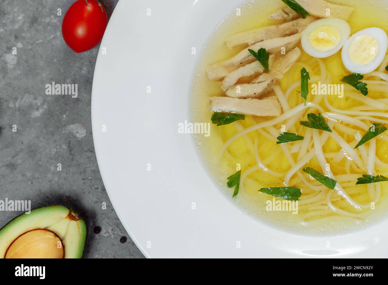 Low-fat chicken broth with a half cooked egg and parsley in a glass ...