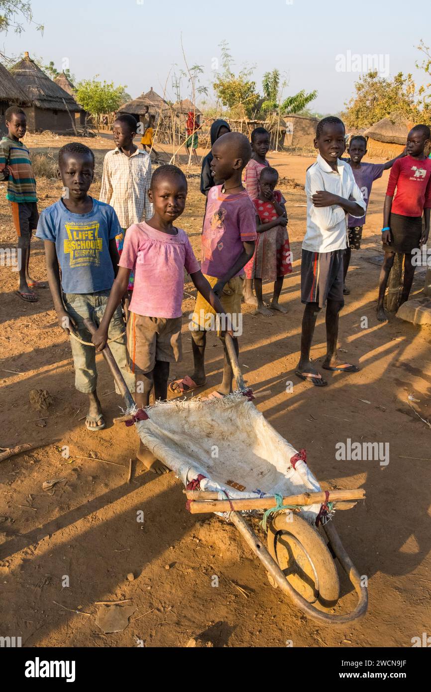 Uganda, Adjumani. A boy with a homemade wheelbarrow in a refugee camp ...