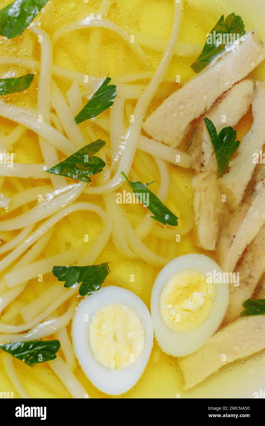 Low-fat chicken broth with a half cooked egg and parsley in a glass ...