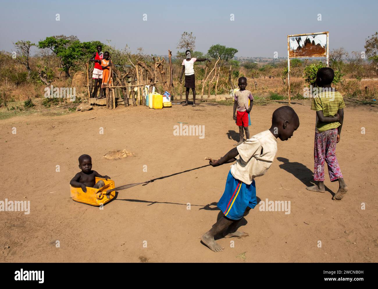 Uganda, Adjumani. Children make sleds out of water jugs to play with in ...