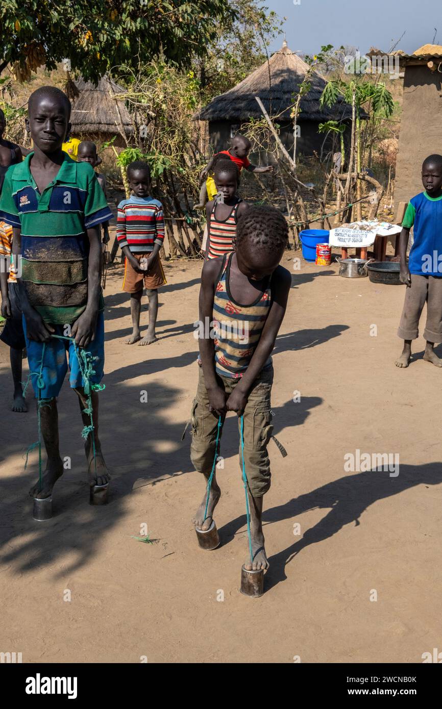 Uganda, Adjumani. Children in a refugee camp play by walking on tin ...