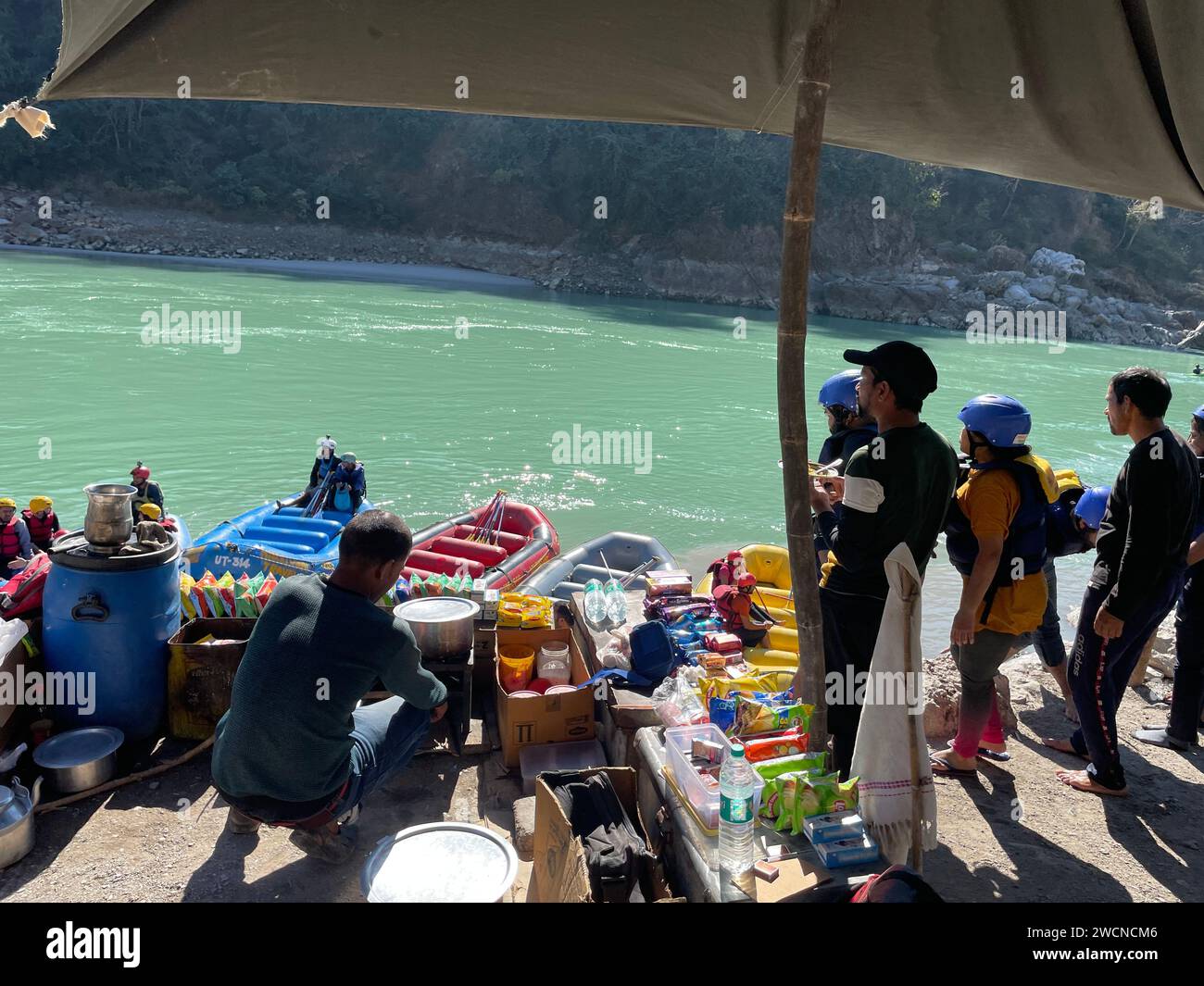 Group of people sitting by a river, sheltered under large umbrellas ...
