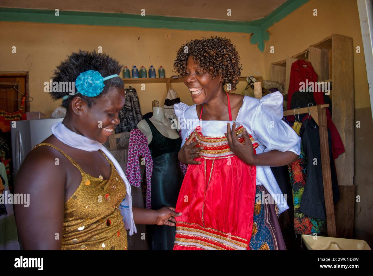 Iganga, Uganda. A woman sells a dress from her shop in the market ...
