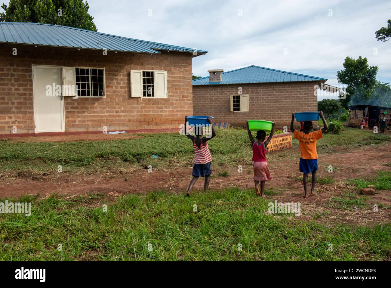 Uganda, Mukono District. Children help with yard work in their ...