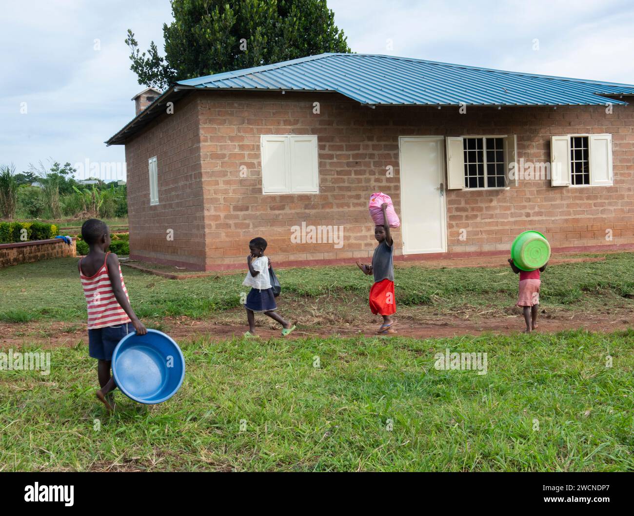 Uganda, Mukono District. Children help with yard work in their ...