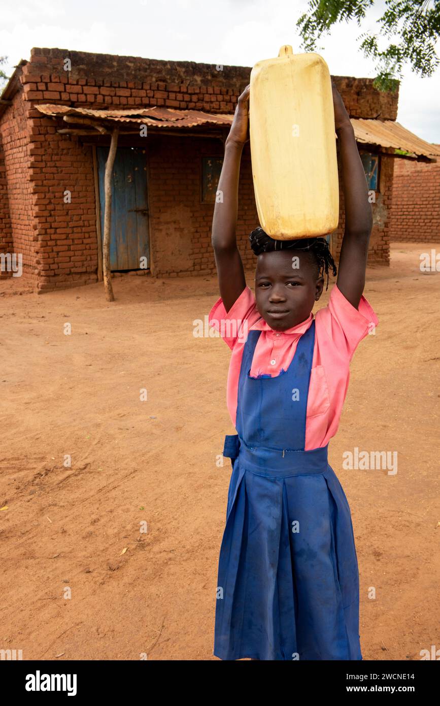 Uganda, Kitgum District. A school girl carries water to her home ...