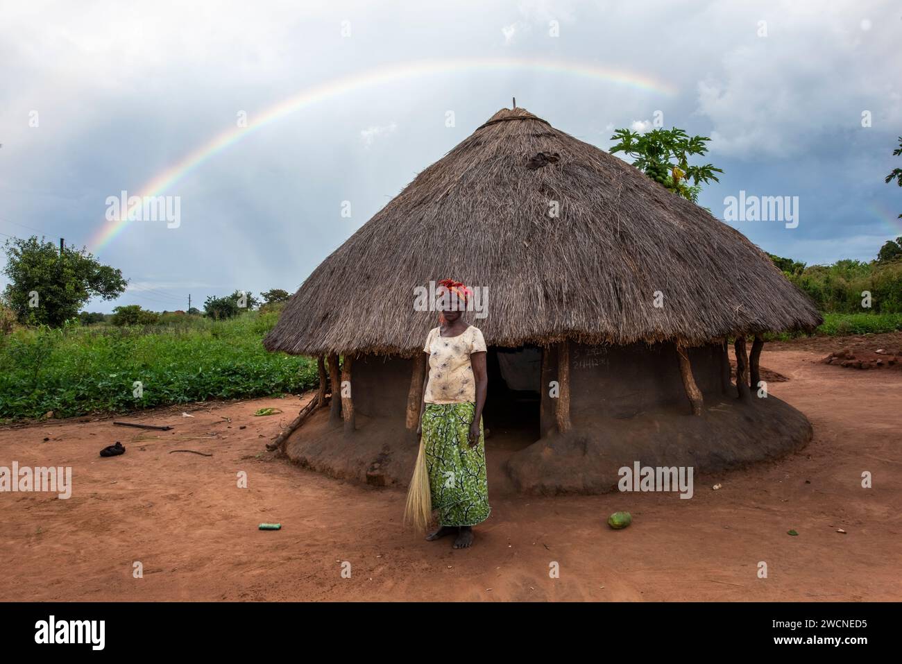 Uganda, Gwendiya, Gulu District. A women poses in front of her round ...