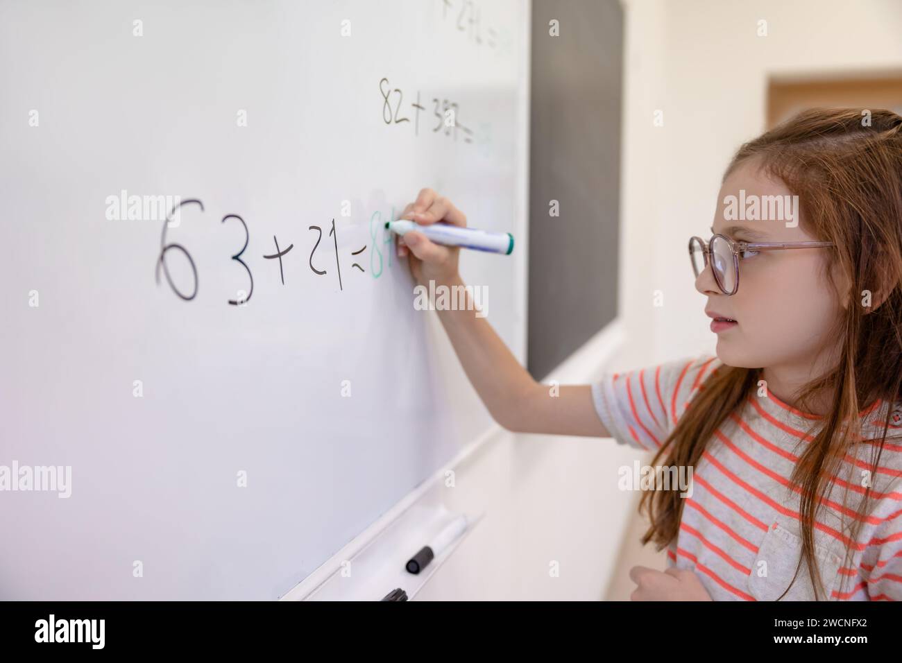 Little girl counting math equation on whiteboard in school Stock Photo ...
