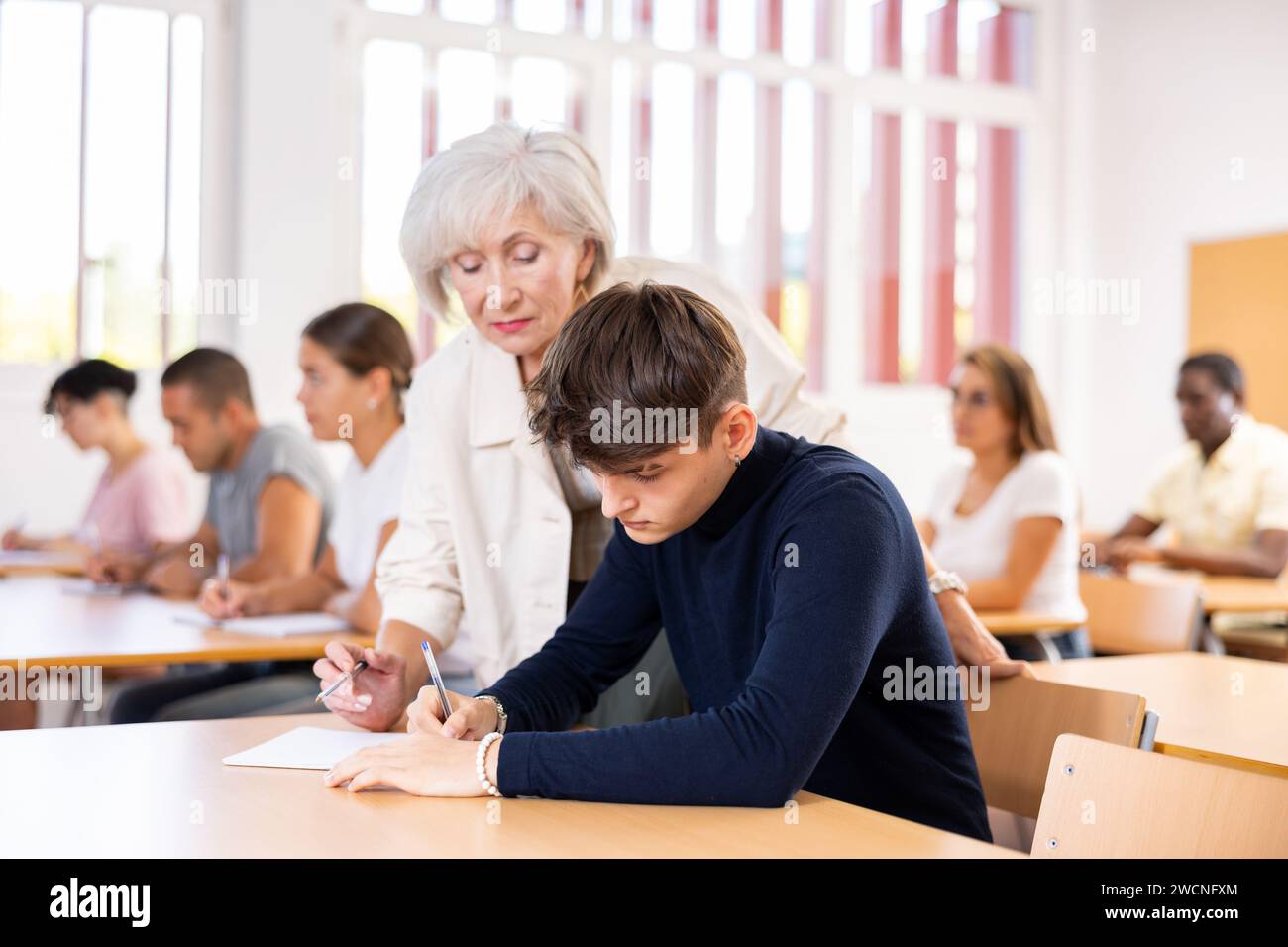 Elderly female teacher helping student solve problem, pointing out ...