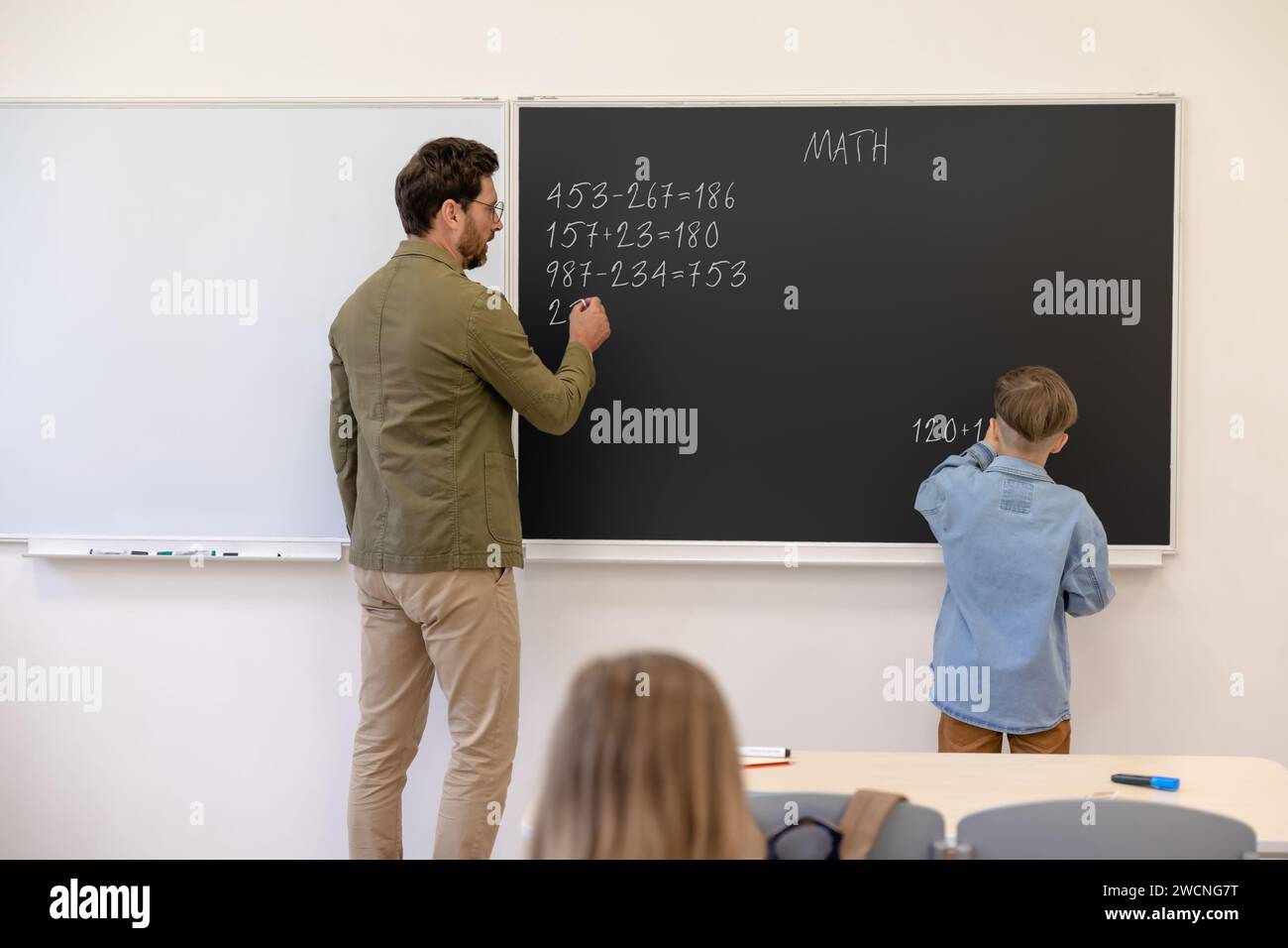 Teacher working with boy pupil at lesson solving math tasks in ...