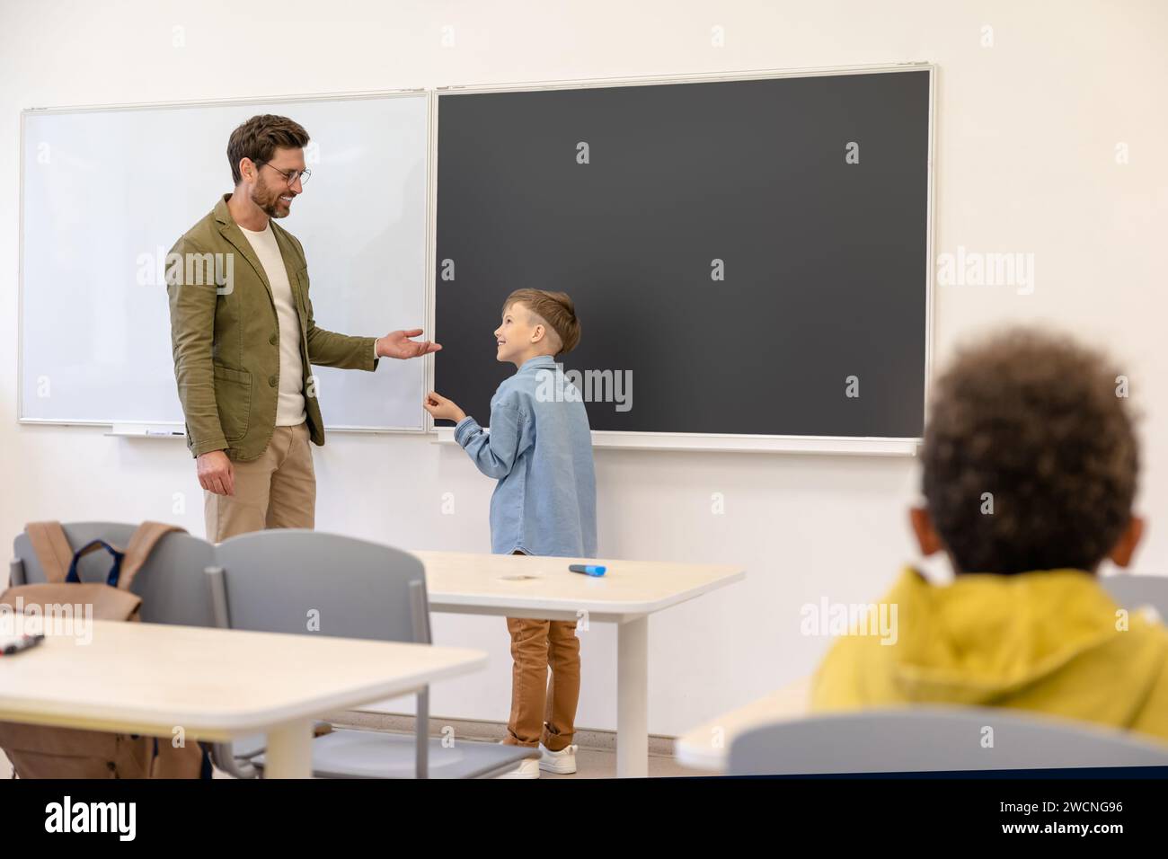 Teacher working with boy pupil at lesson solving math tasks in ...