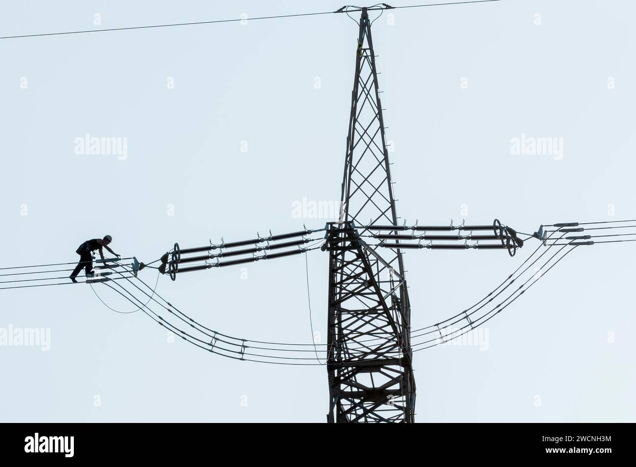 Overhead line fitter working on a high-voltage pylon, overhead lines ...