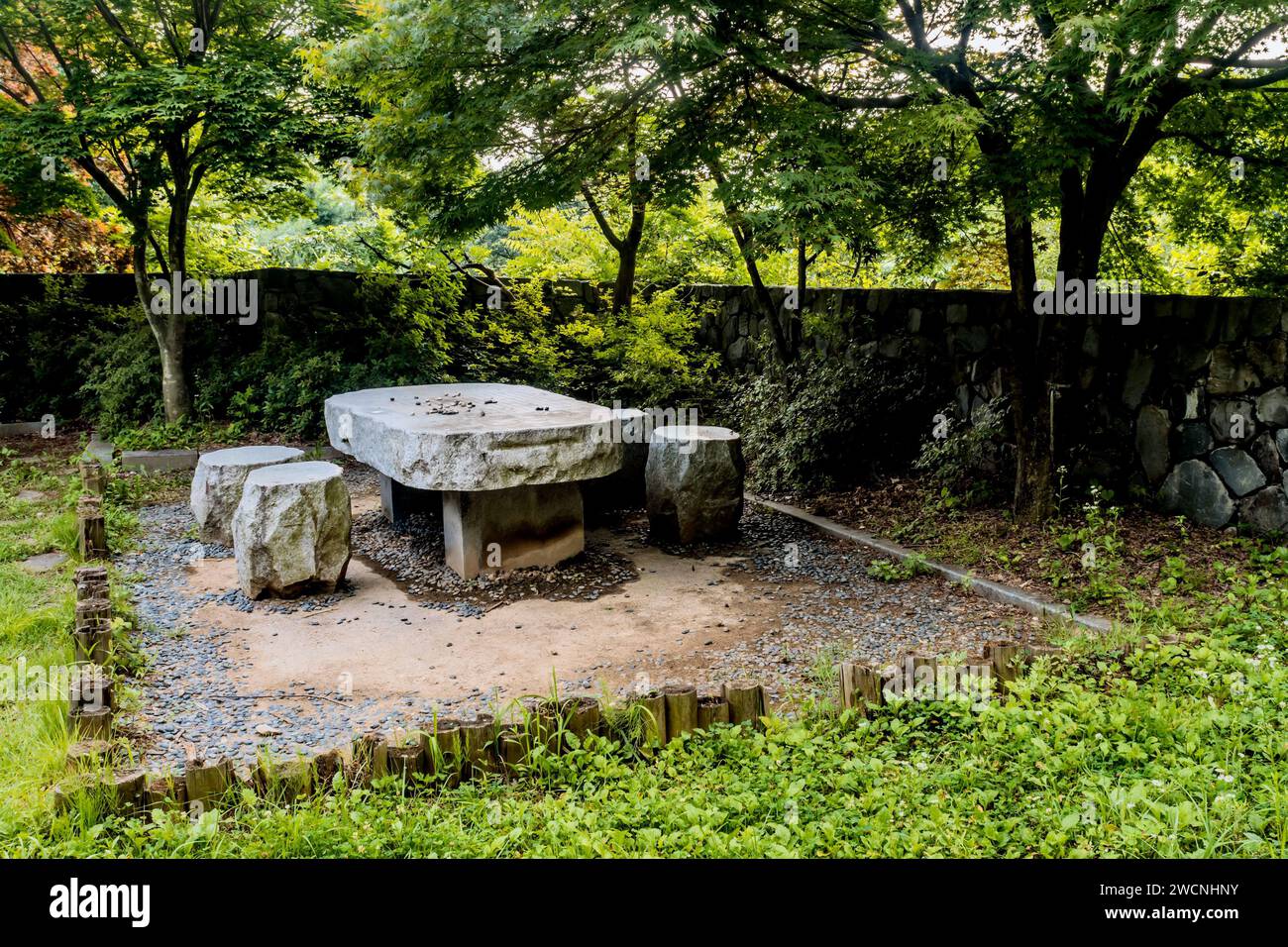 Stone picnic table on concrete under shade trees in verdant ...