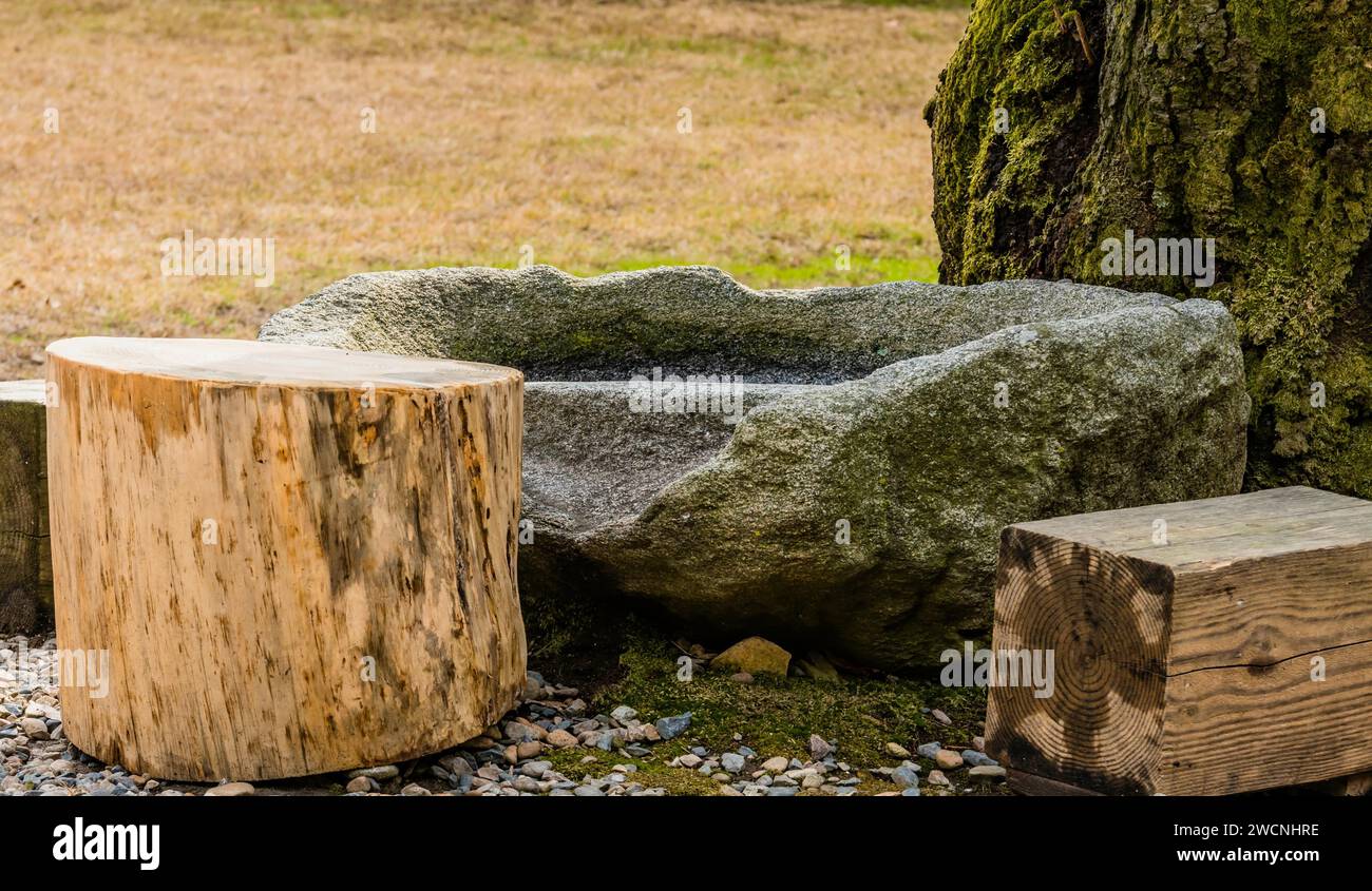 Man made concrete stool and three wooden stools on ground covered with ...
