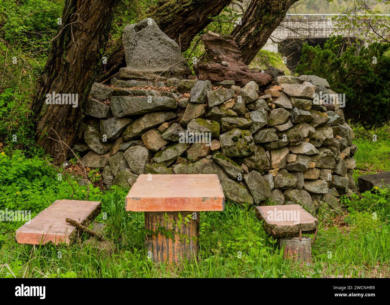 Concrete picnic table in front of large pile of rocks stacked next to ...
