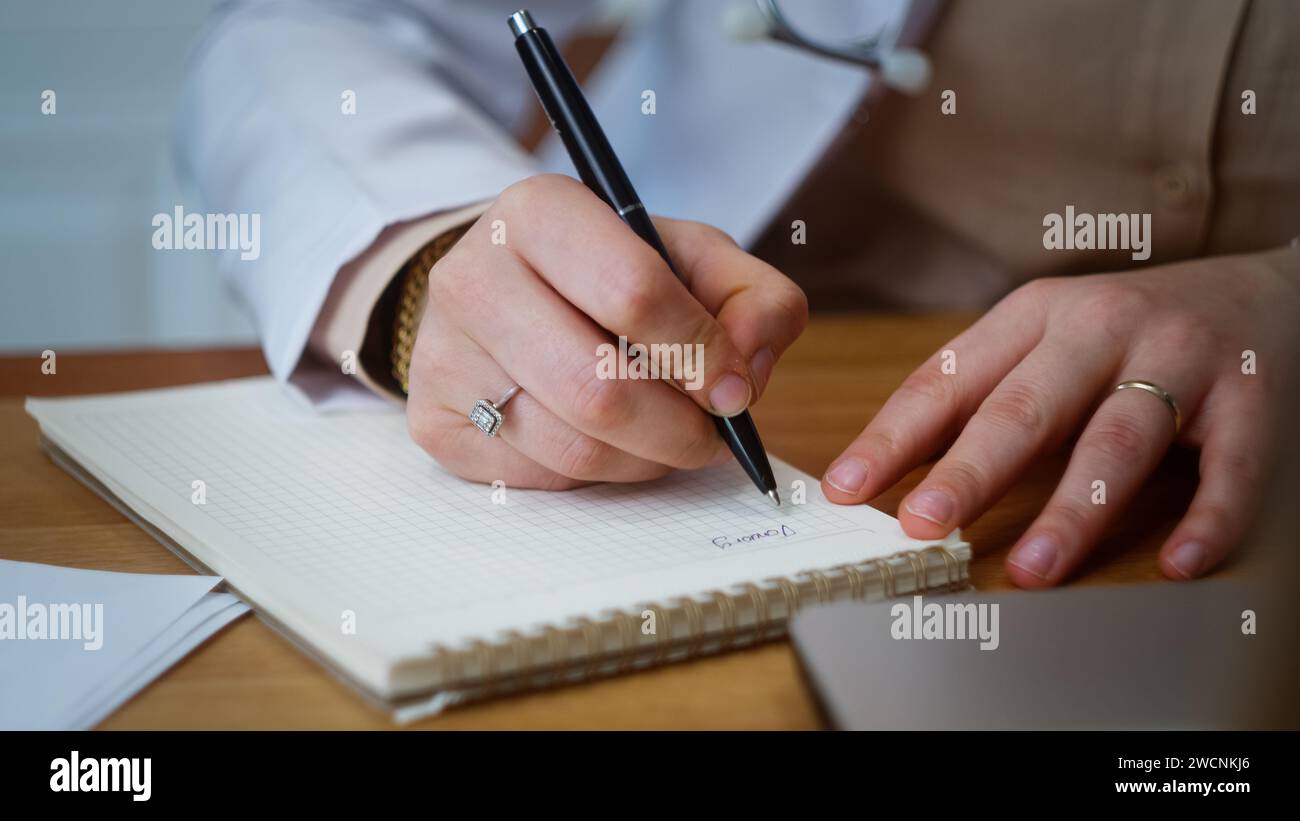 Close up female doctor taking notes in registration book, managing ...