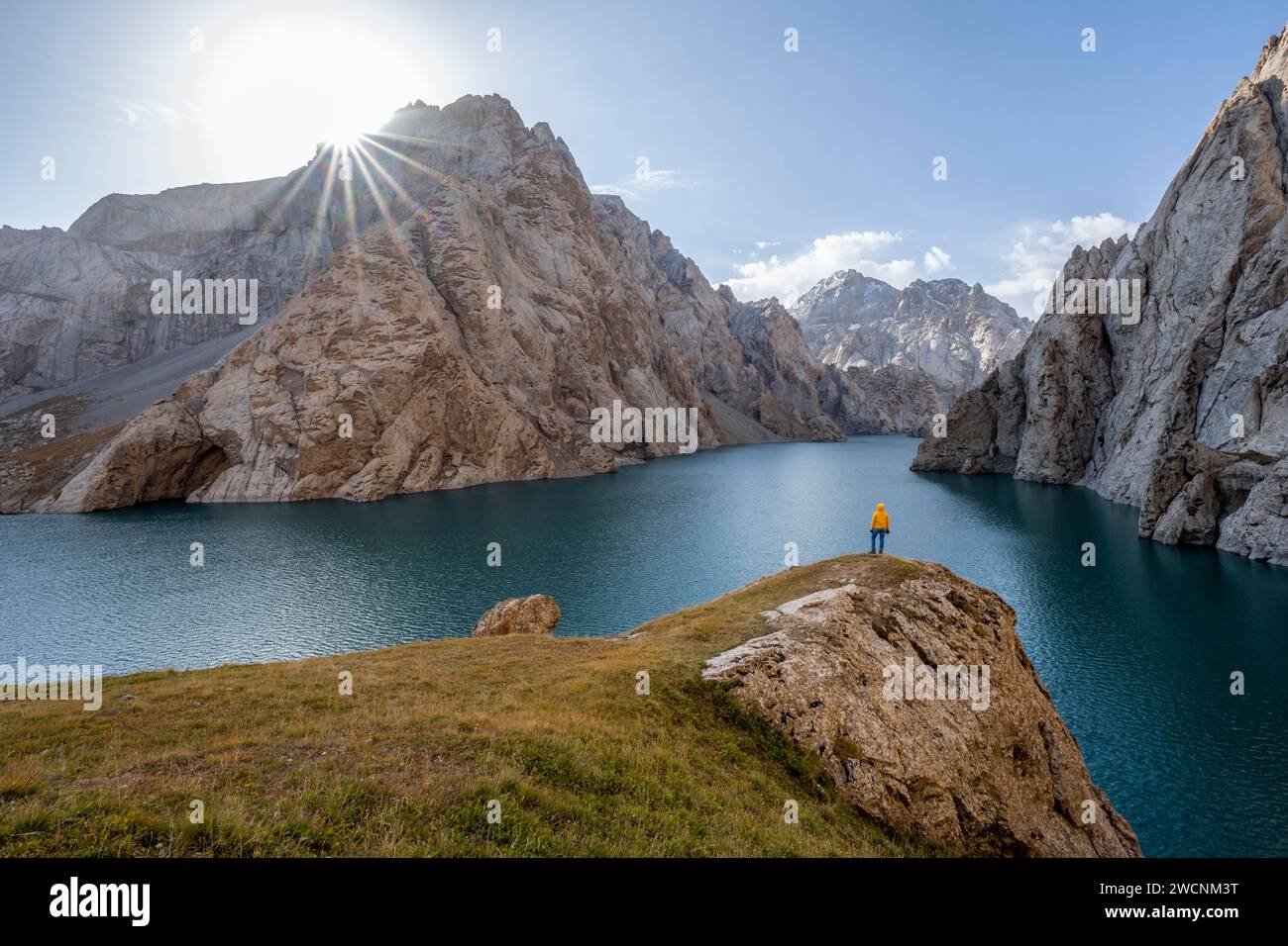 Tourist at the blue mountain lake between rocky steep mountain peaks ...