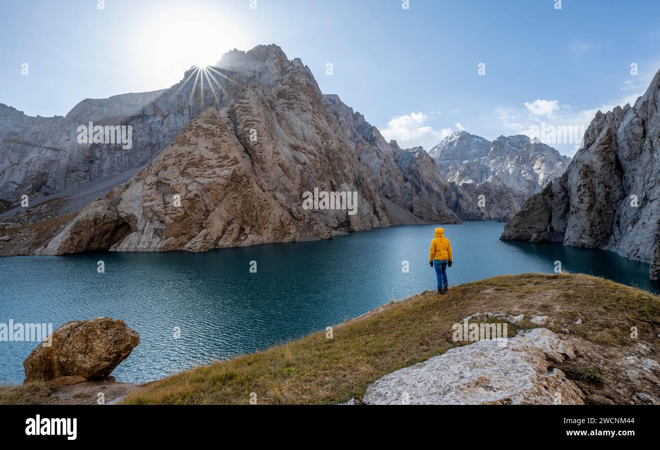 Tourist at the blue mountain lake between rocky steep mountain peaks ...